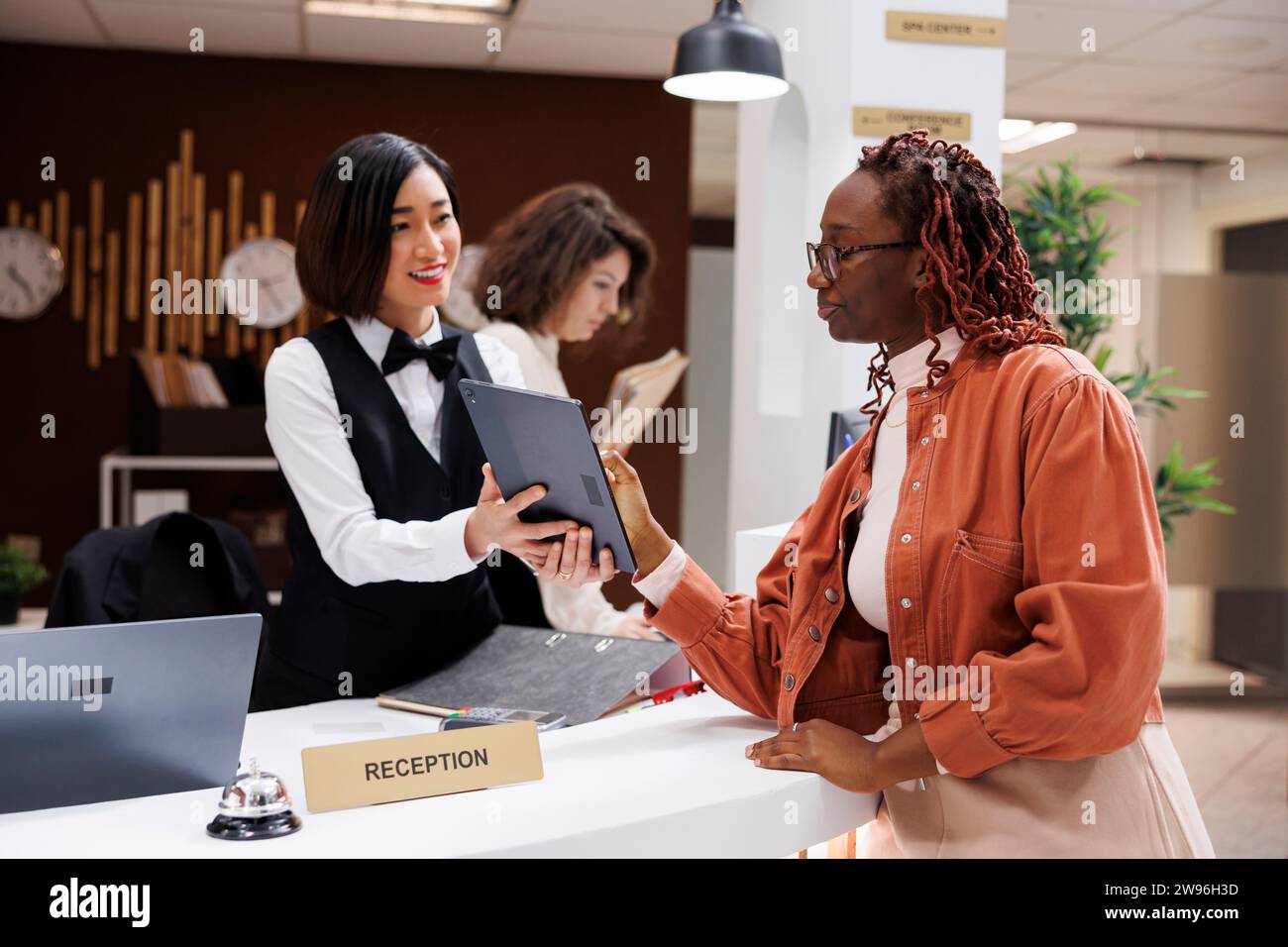 Young woman checking in at luxury hotel, filling in registration forms ...