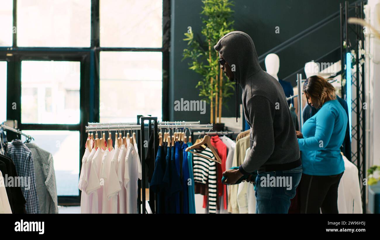 African american robber stealing fashionable outfit, trying to run from ...