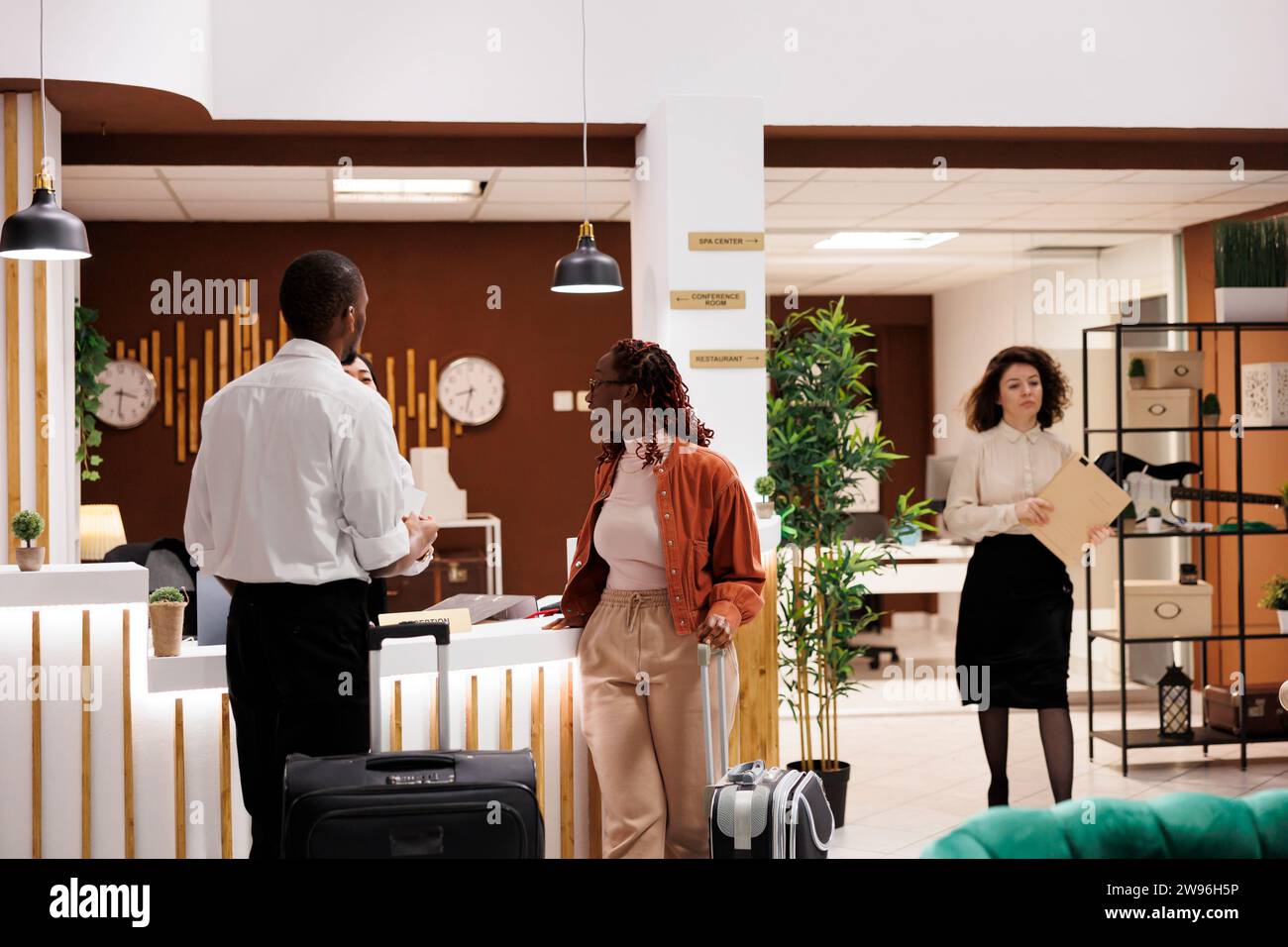 Two people checking in at hotel and taking key card from reception ...