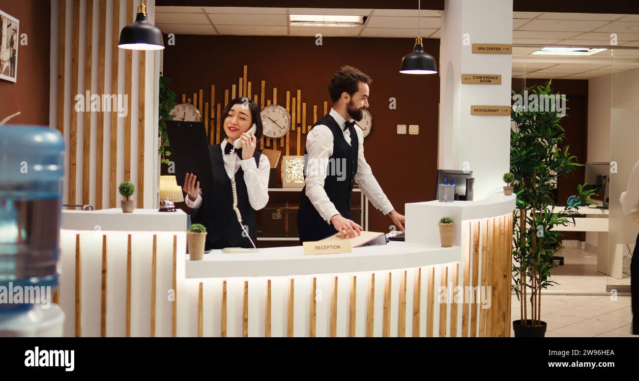 Smiling hotel administrator discussing holiday package options and amenities upgrade with ...