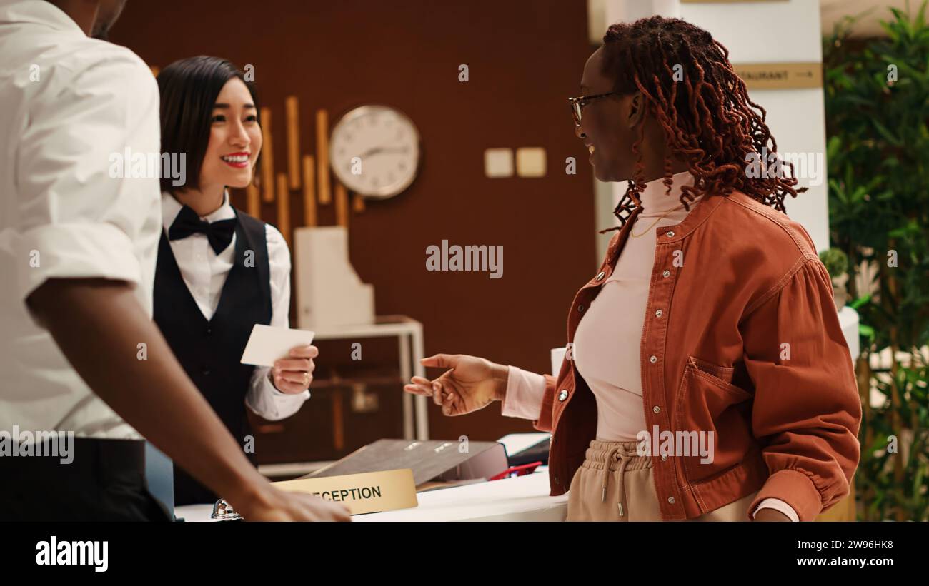 Happy receptionist handing relaxed smiling newlywed couple room access ...