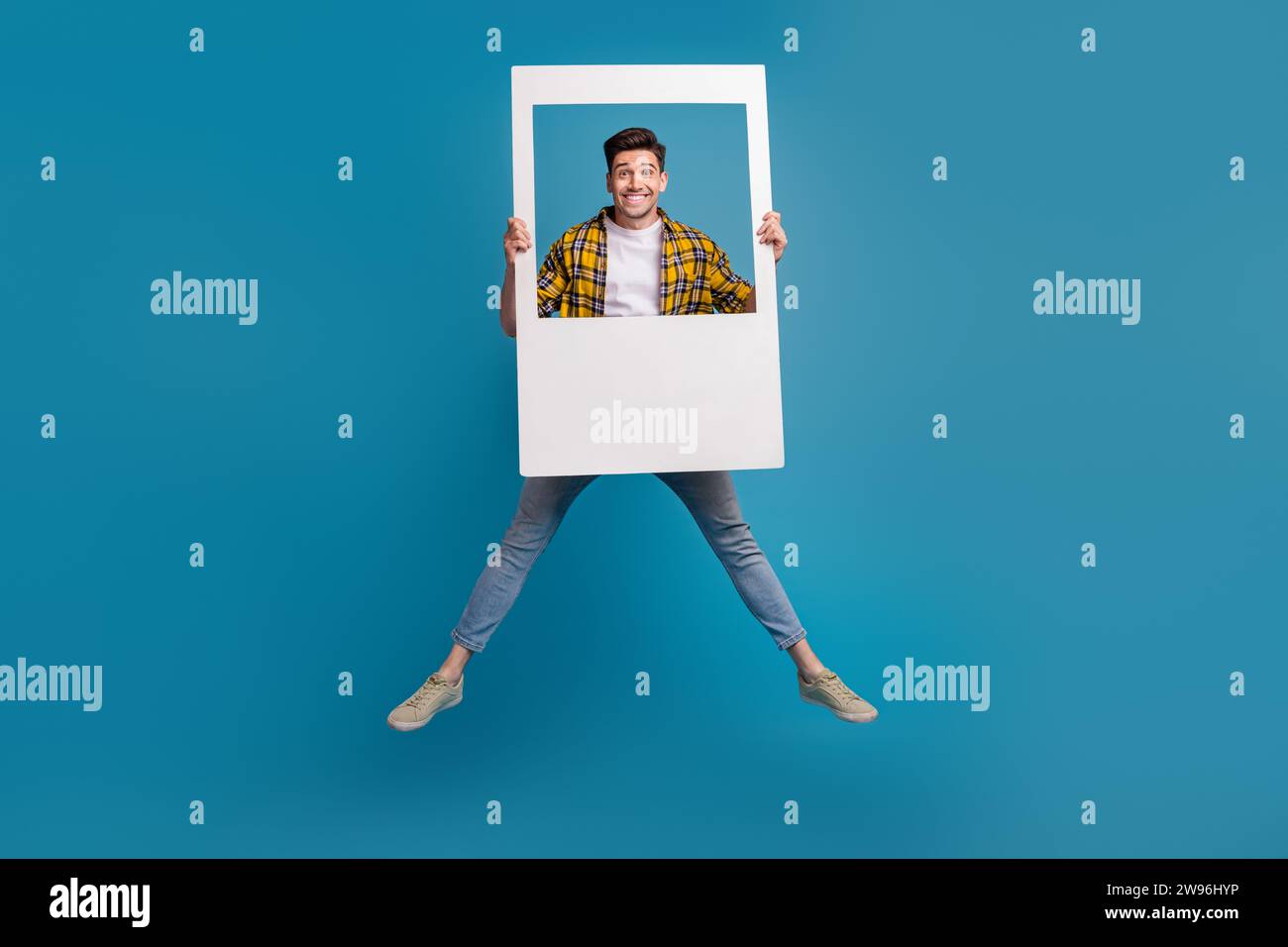 Full body shooting young funny guy jumping happy smile holding portrait ...