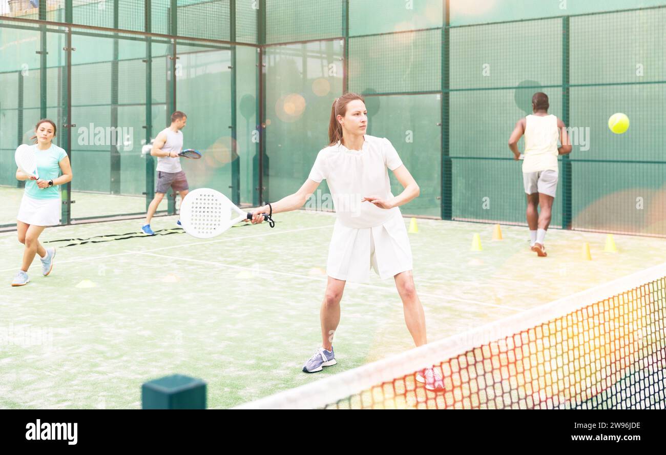 Young sporty woman performing basic strokes during paddle tennis group ...