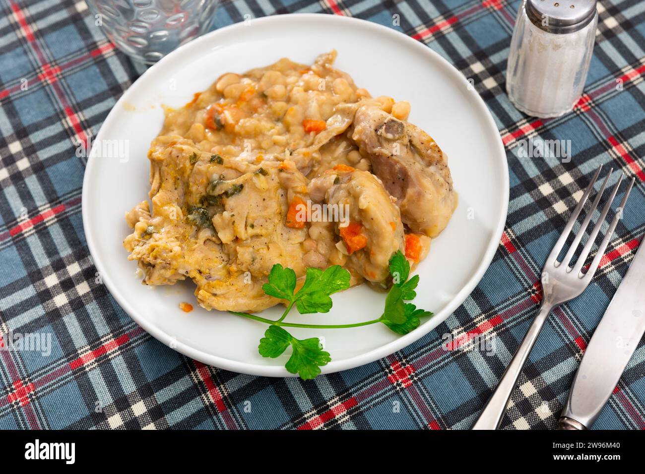 Fried rabbit leg with stewed beans on plate. Garnish is decorated with ...