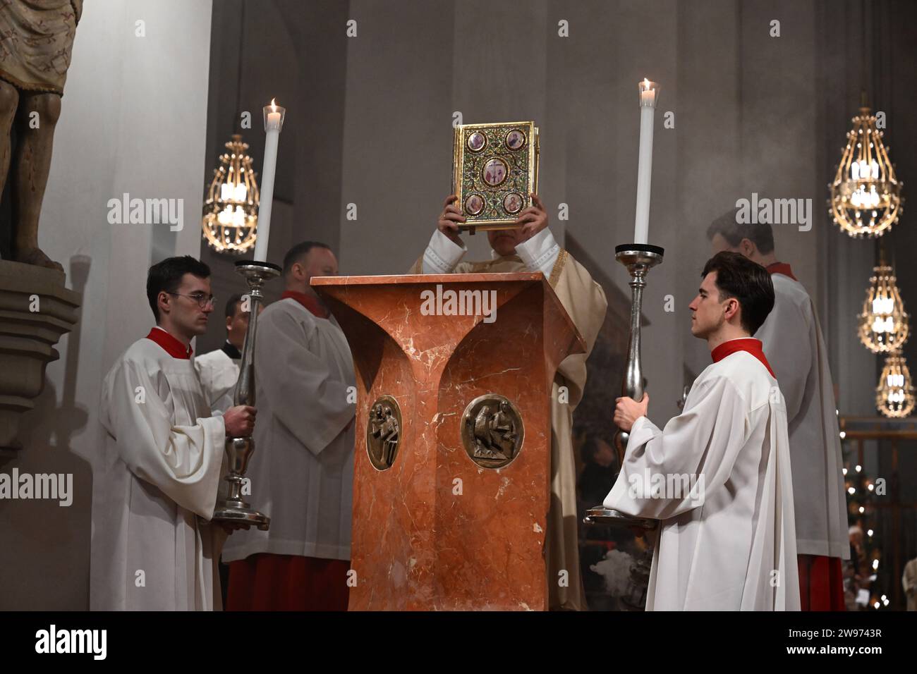 Munich, Germany. 24th Dec, 2023. A priest holds up the Holy Scriptures ...