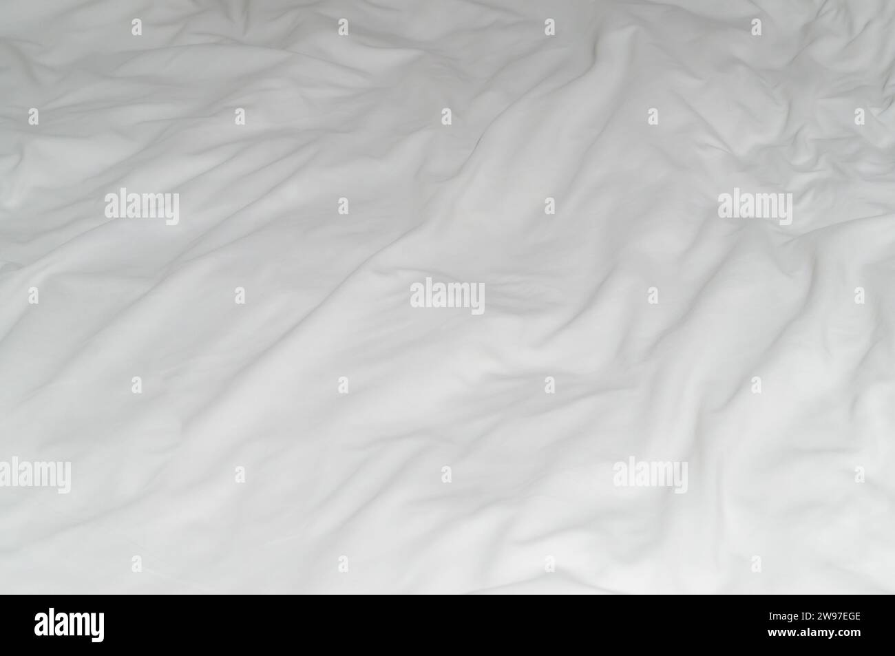 White crumpled or wrinkled bedding sheet or blanket with pattern after ...