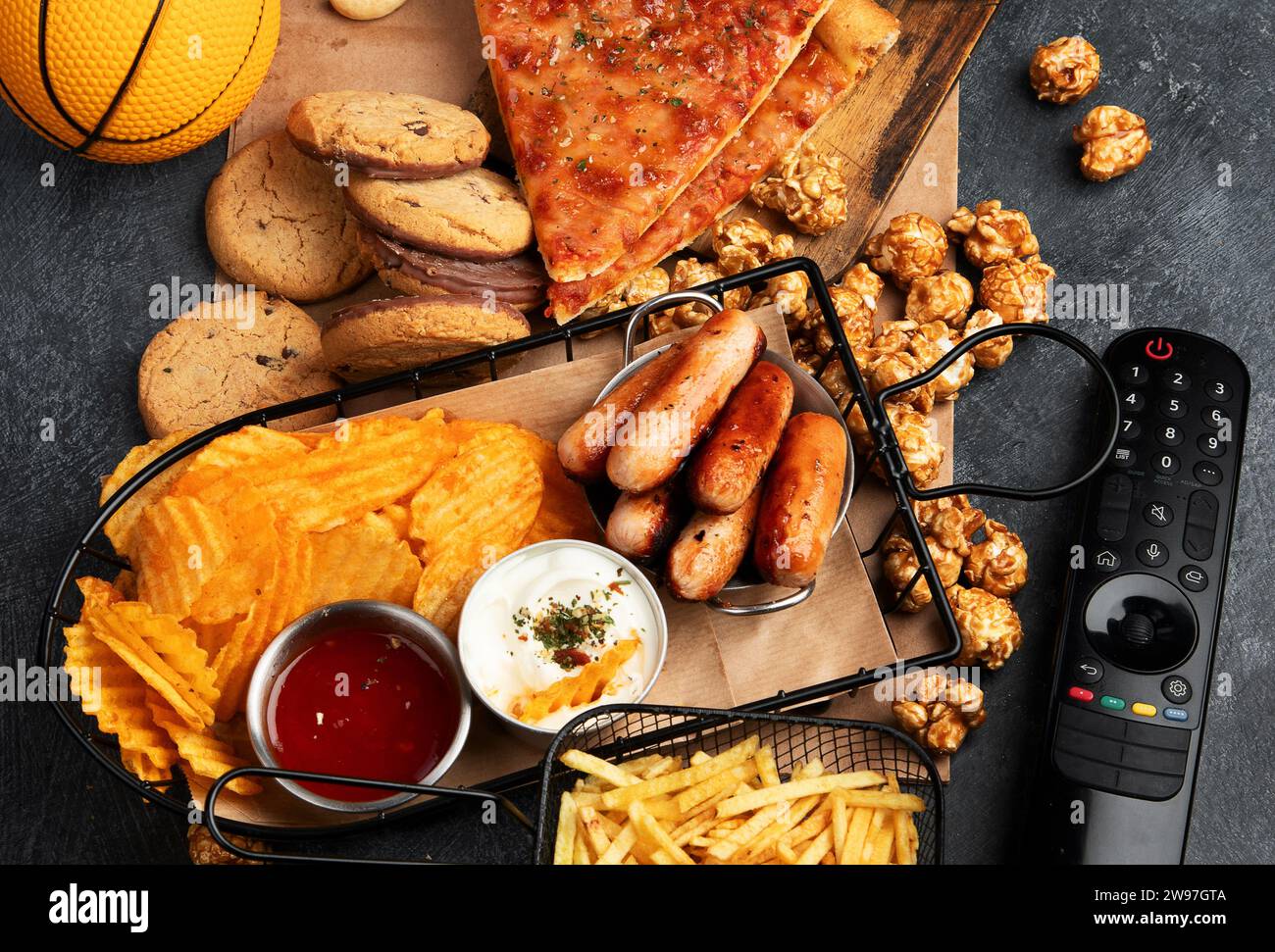 Unhealthy food i basket. TV remote control and snacks - chips, popcorn ...