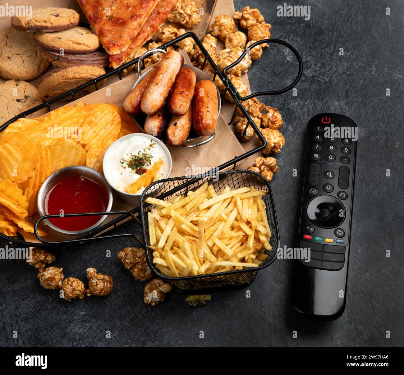 Unhealthy food i basket. TV remote control and snacks - chips, popcorn ...
