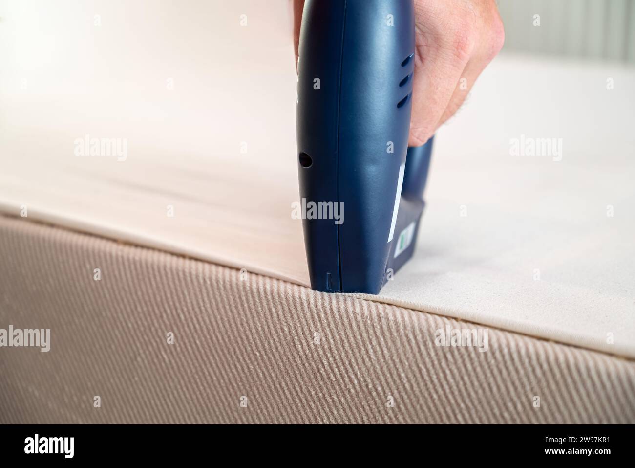 Worker stapling sofa lining with electric staple gun Stock Photo - Alamy