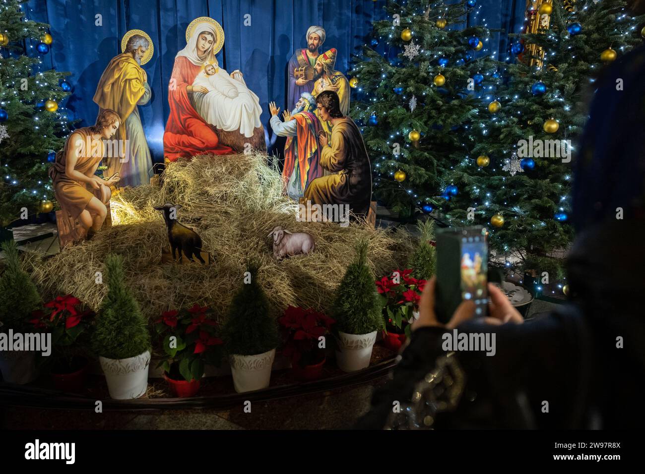 Kyiv, Ukraine. 24th Dec, 2023. A woman takes a photo of a Christmas ...