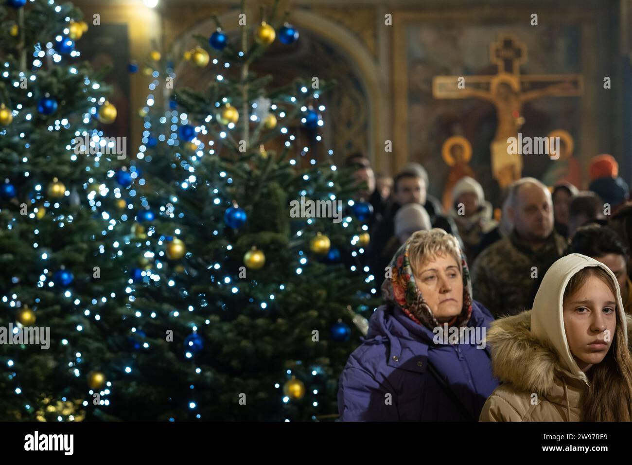 Kyiv, Ukraine. 24th Dec, 2023. People stand next to a Christmas tree as ...