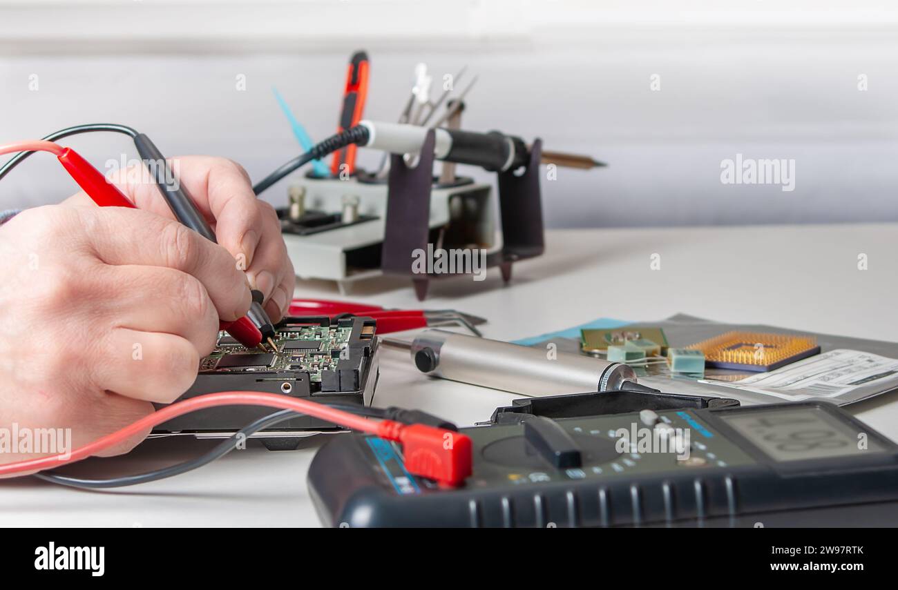 Close-up of a technician's hands in a workshop. The repairer is using a ...