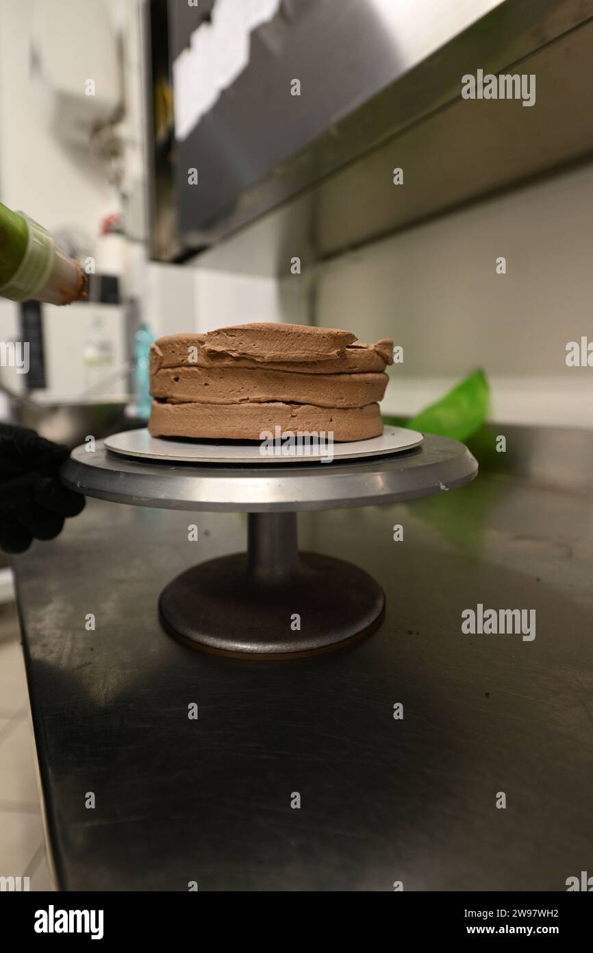 layered dark chocolate frosted cake and cream preparation in ...