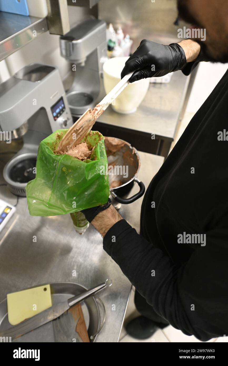 pastry chef using piping bag filled with butter cream to decorate a ...