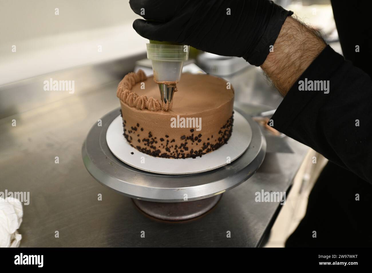 pastry chef using piping bag filled with butter cream to decorate a ...