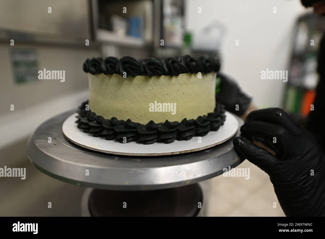 pastry chef wear gloves prepare pistachio frosted icing cake for ...
