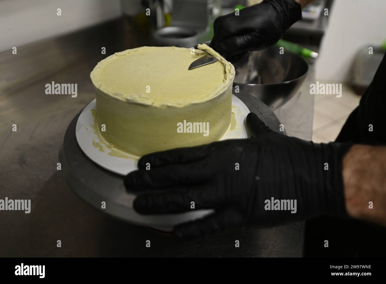 pastry chef wear gloves prepare pistachio frosted icing cake for ...