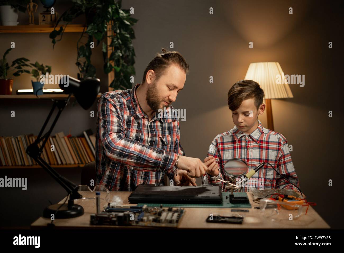 A father teaches his son how to repair a broken laptop and a damaged ...