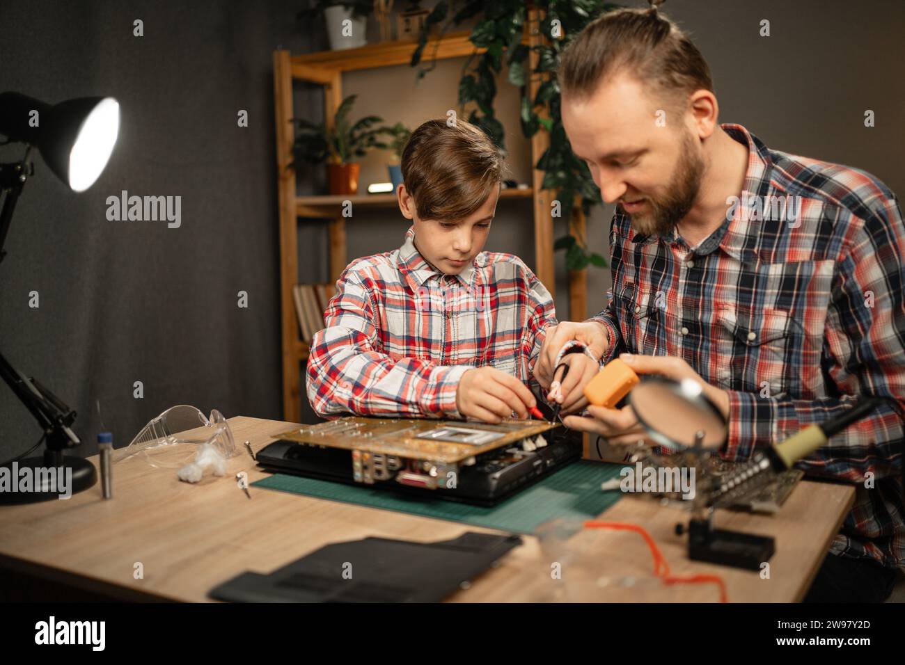 Father and son spend time together repairing a broken laptop, using a ...