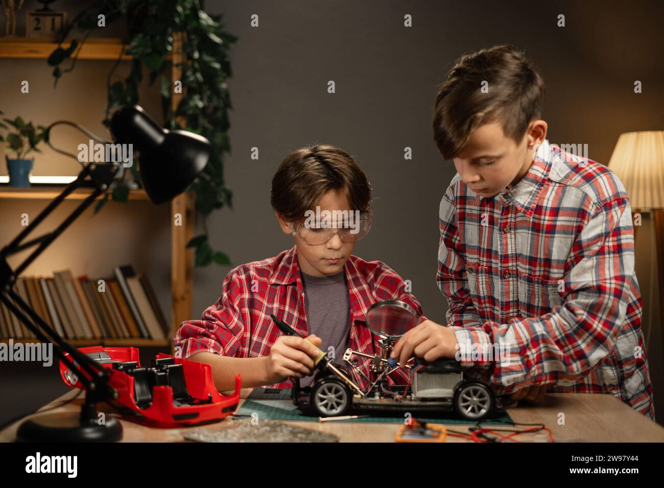 Two teenage schoolboys soldering wires in hobby electronics project ...