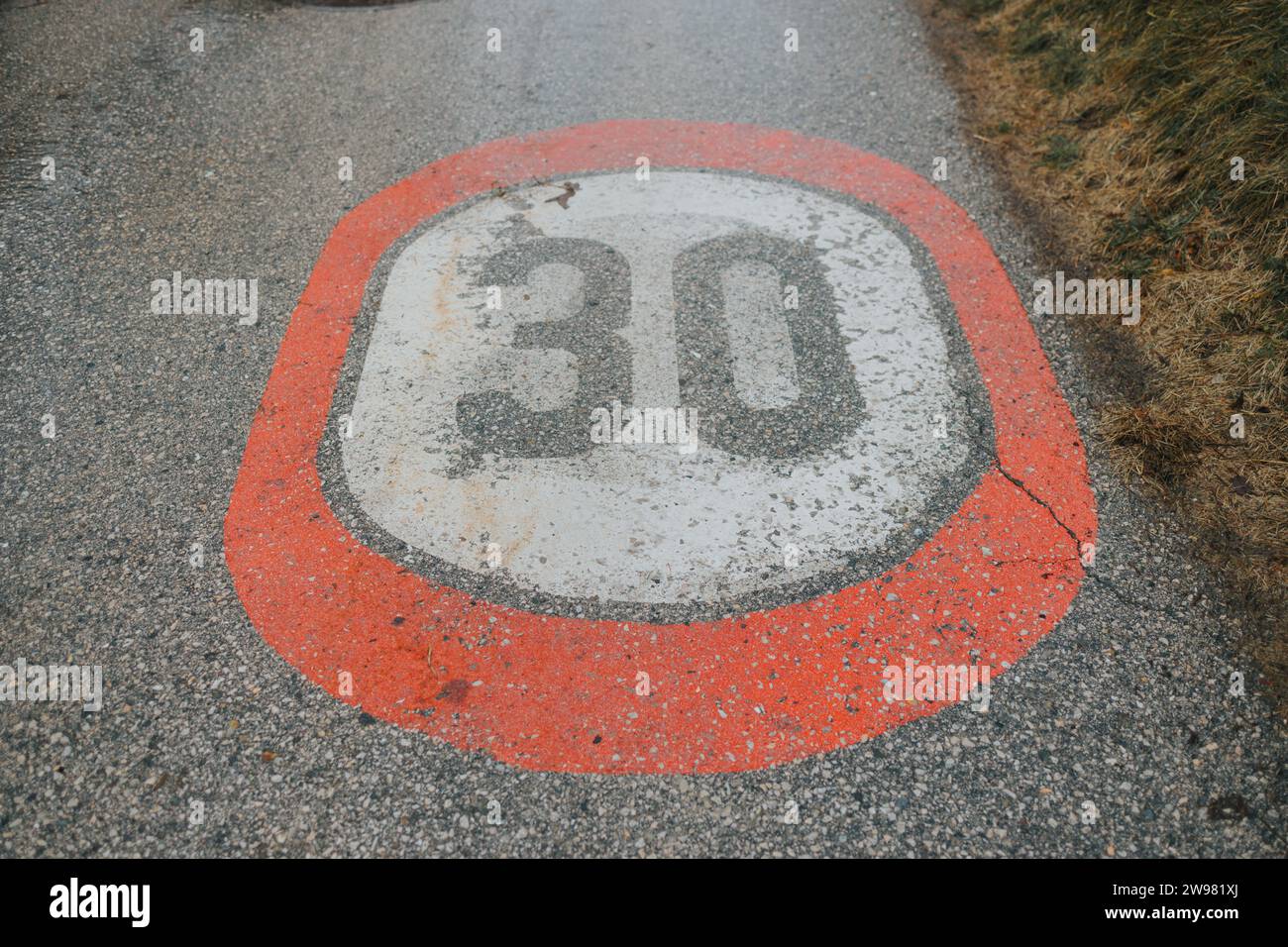 A red and white street sign painted on an asphalt pavement in a ...