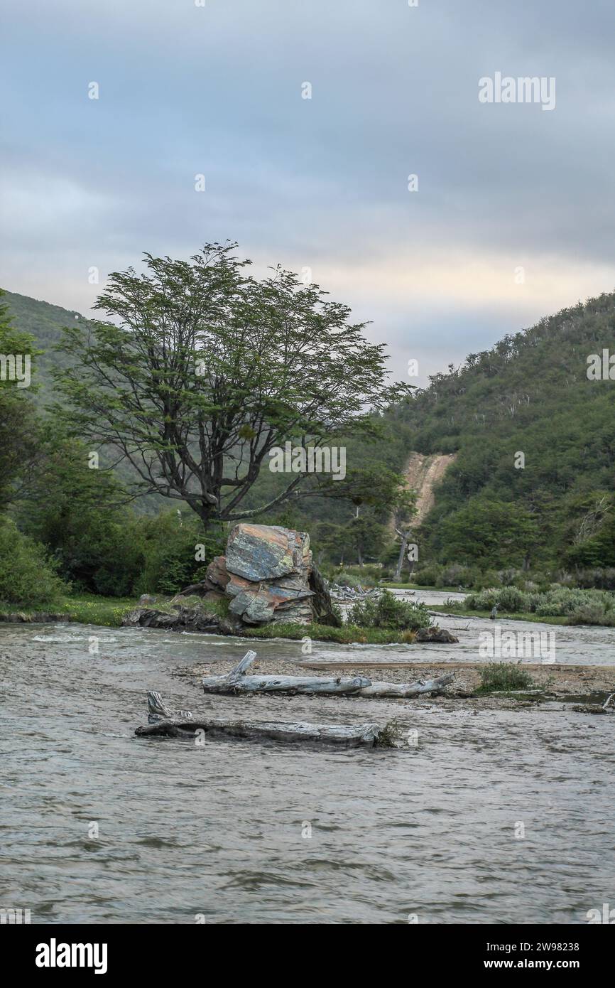 A tranquil river meandering between trees and rocky outcroppings ...