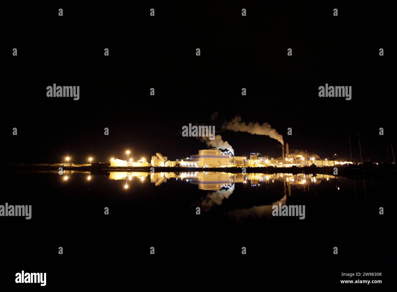 A paper mill is reflected perfectly in water at night in Port Angeles ...