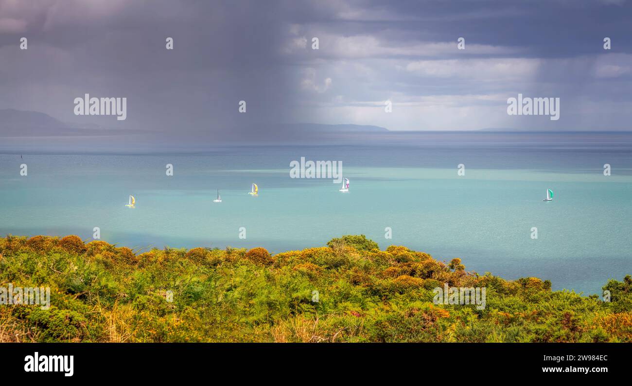 In the midst of showers and sunshine, sailboats on the Irish Sea off of ...