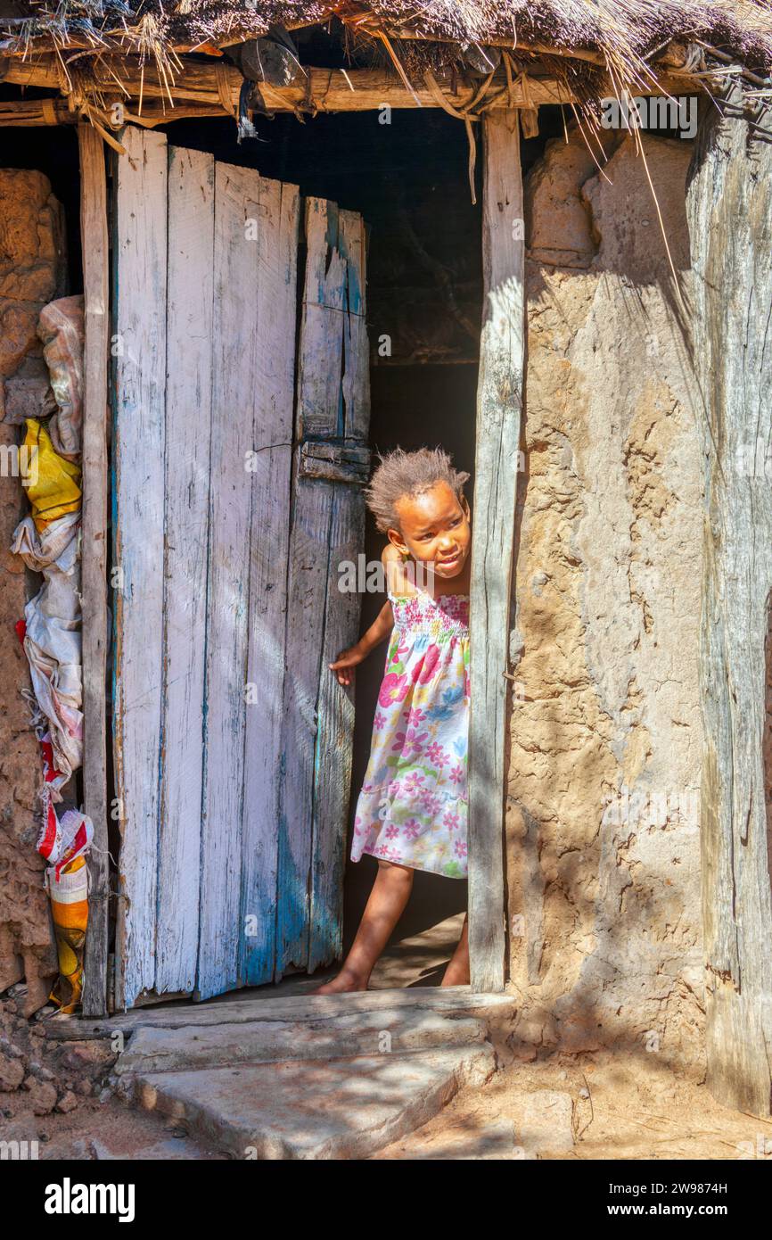 african girl standing in front of her shack, mud house, in an informal ...