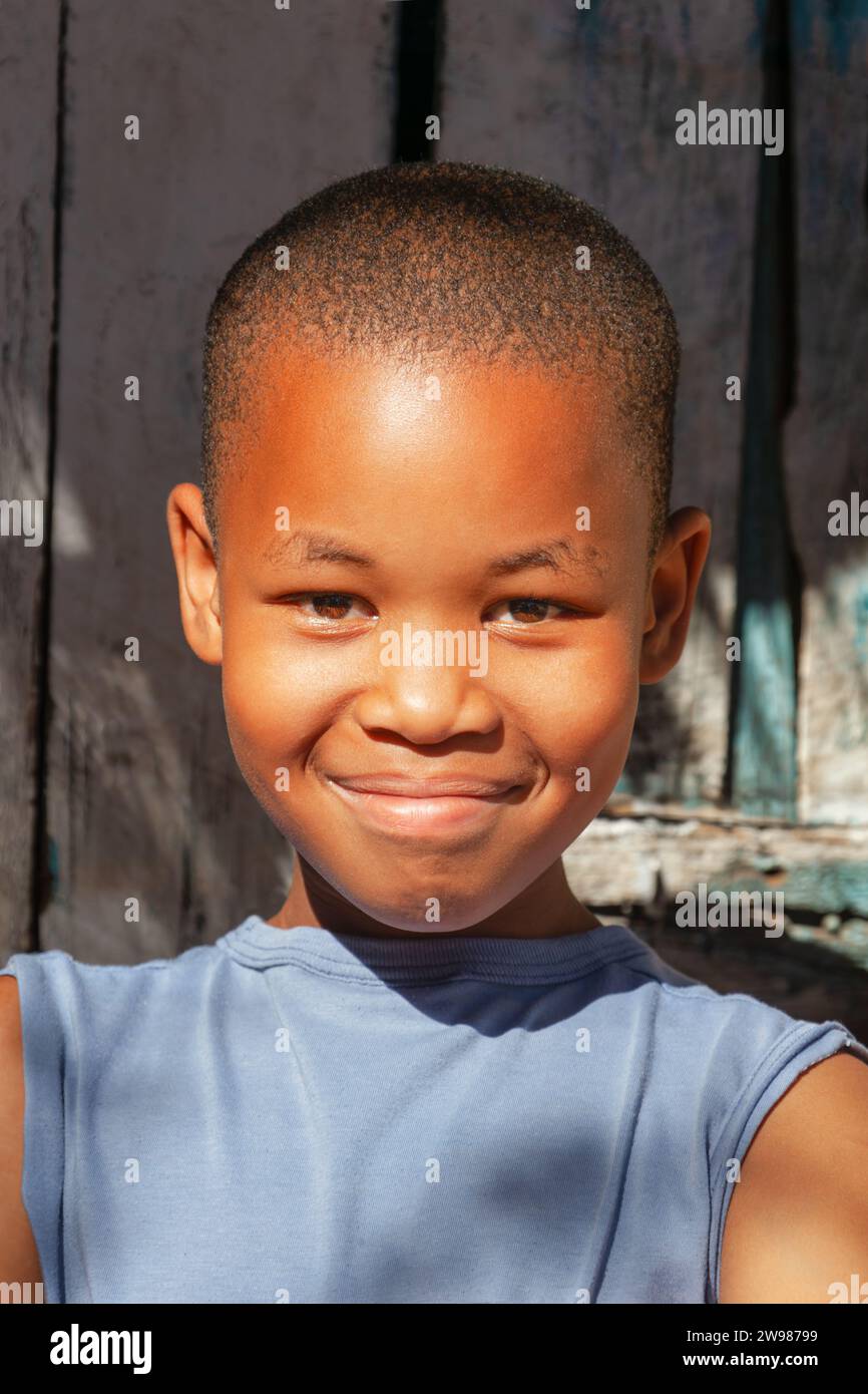 african child in the village, standing in front of the hut door in the ...