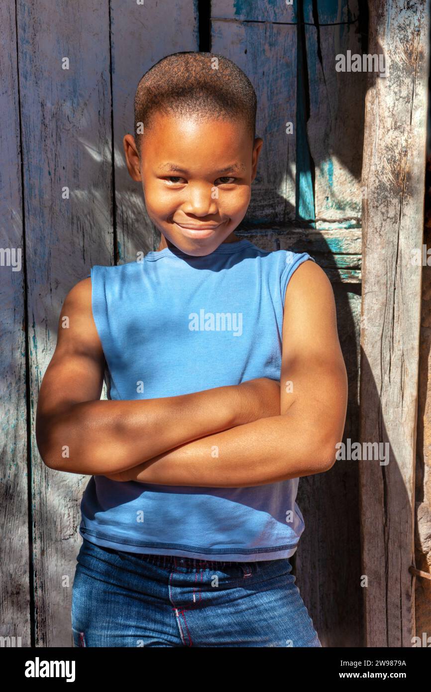 african kid standing with arms crossed in the door of her shack, mud ...
