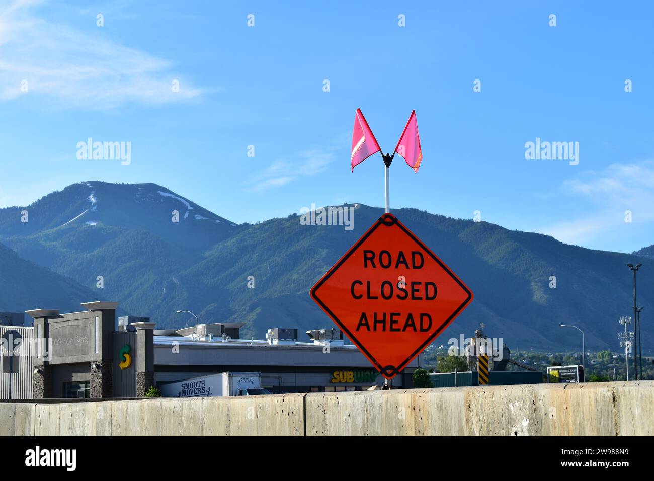 "ROAD CLOSED AHEAD" orange traffic warning sign with two small flags on ...