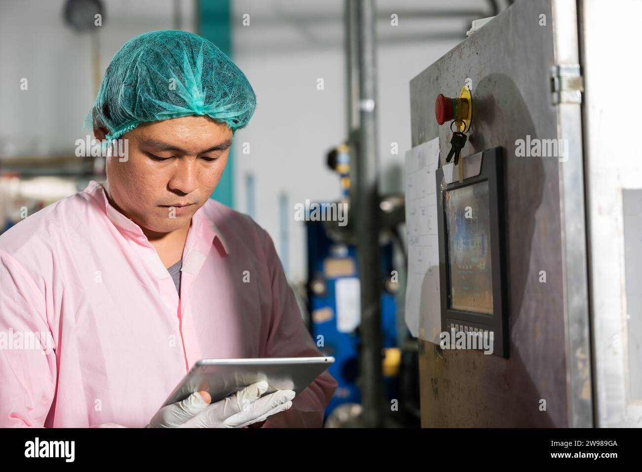 Worker using tablet in beverage factory oversees soda water filling ...
