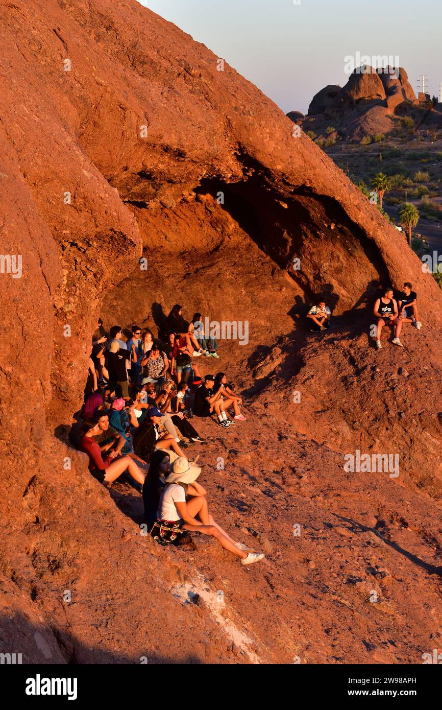 People sitting on the red sandstone of Hole in the Rock while enjoying ...