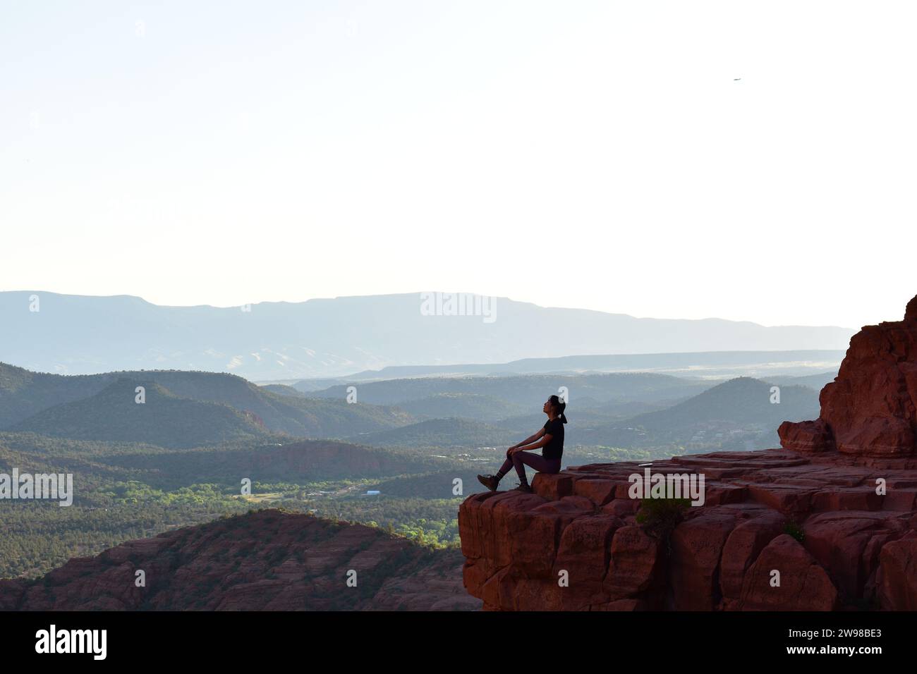 Person sitting on stone ledge overlooking the Arizona desert landscape ...