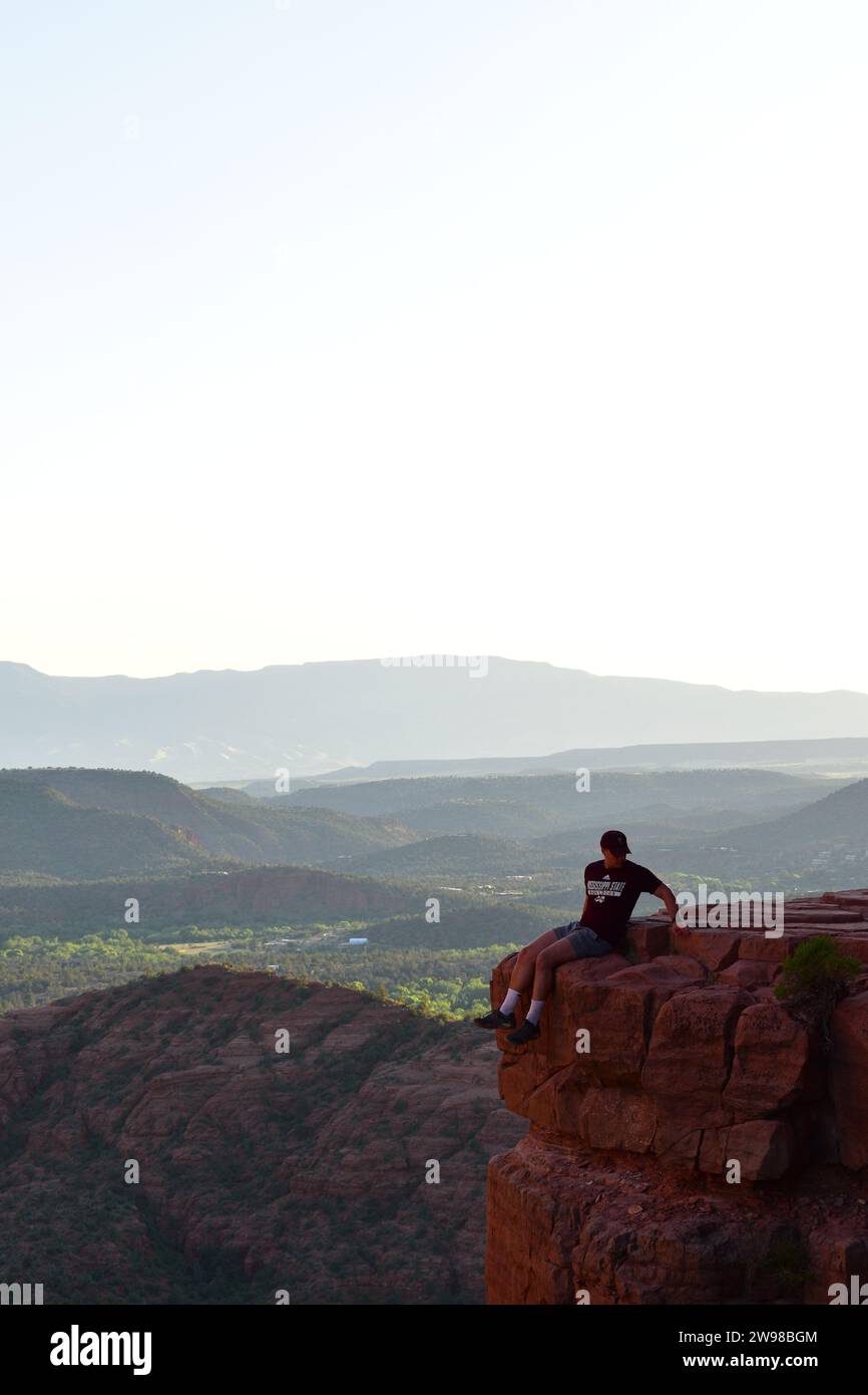 Person sitting on stone ledge overlooking the Arizona desert landscape ...