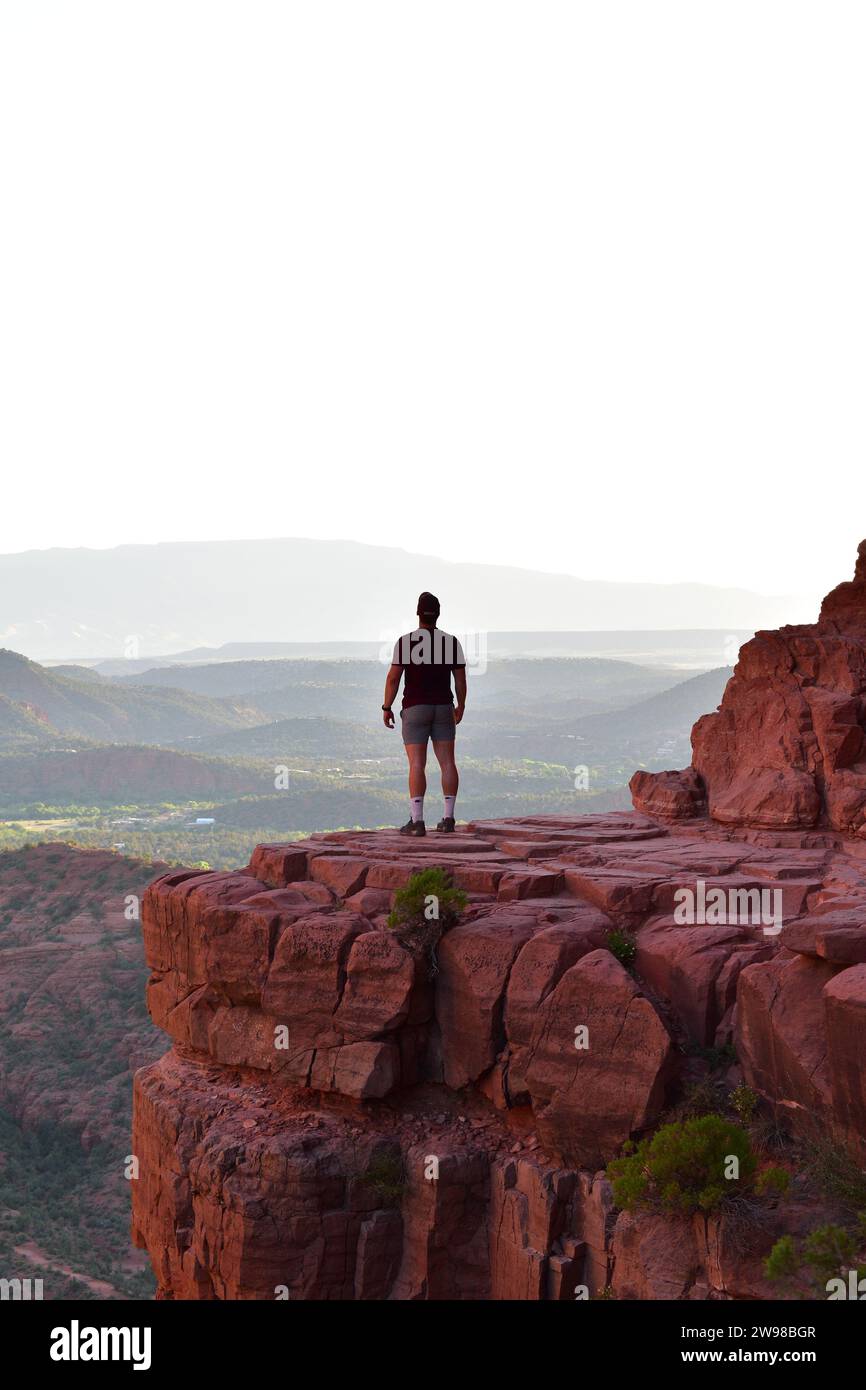 Person standing on stone ledge overlooking the Arizona desert landscape ...