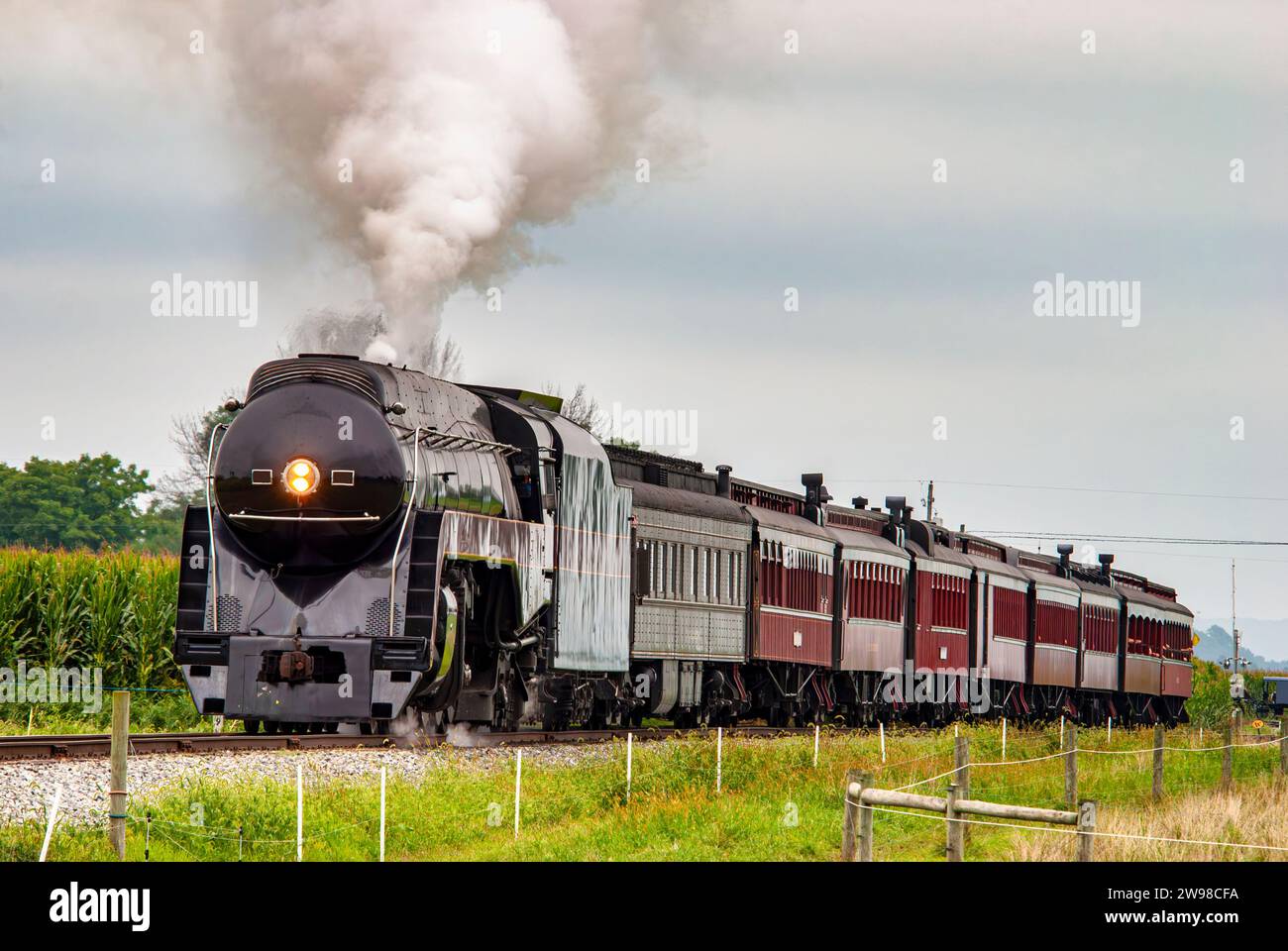 A vintage steam locomotive is chugging along a railway track, emitting ...