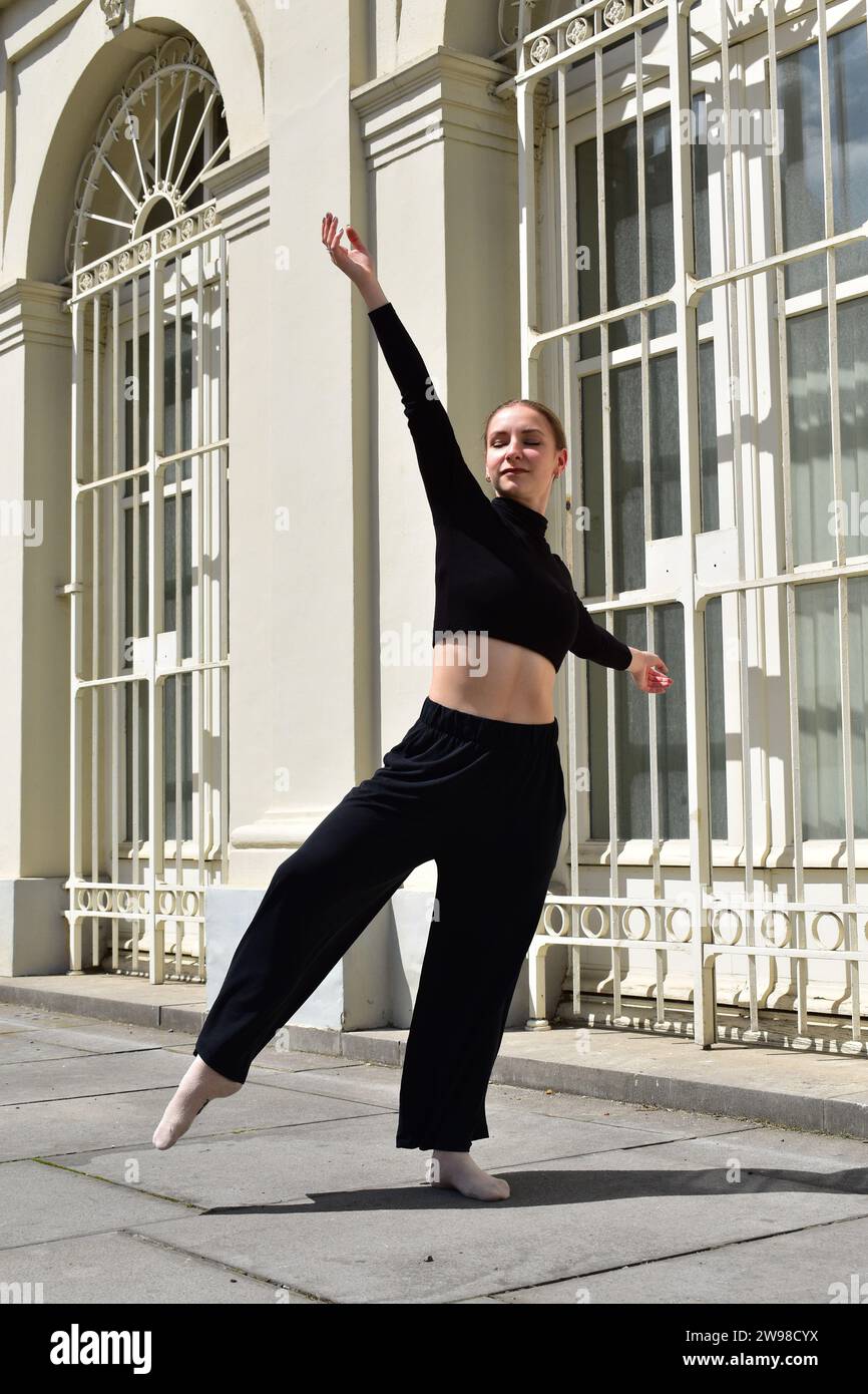 Young woman in black outfit performing a contemporary dance move in ...