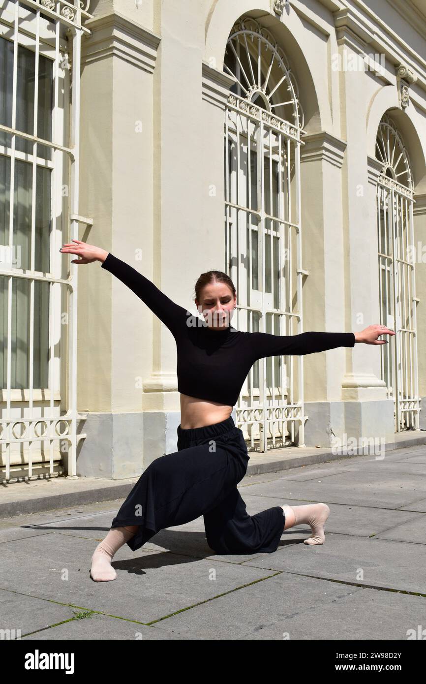 Young woman in black outfit performing a contemporary dance move in ...