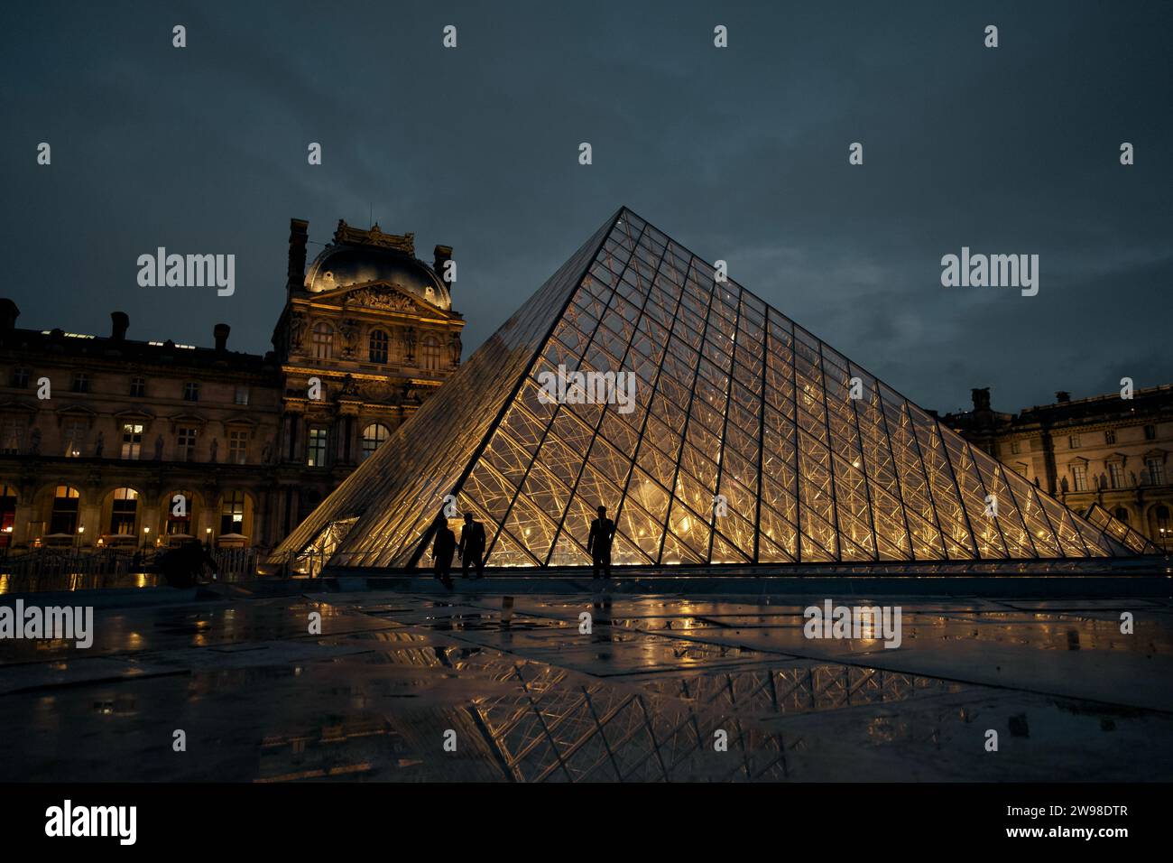 A nighttime view of the iconic Louvre Museum in Paris, illuminated by ...