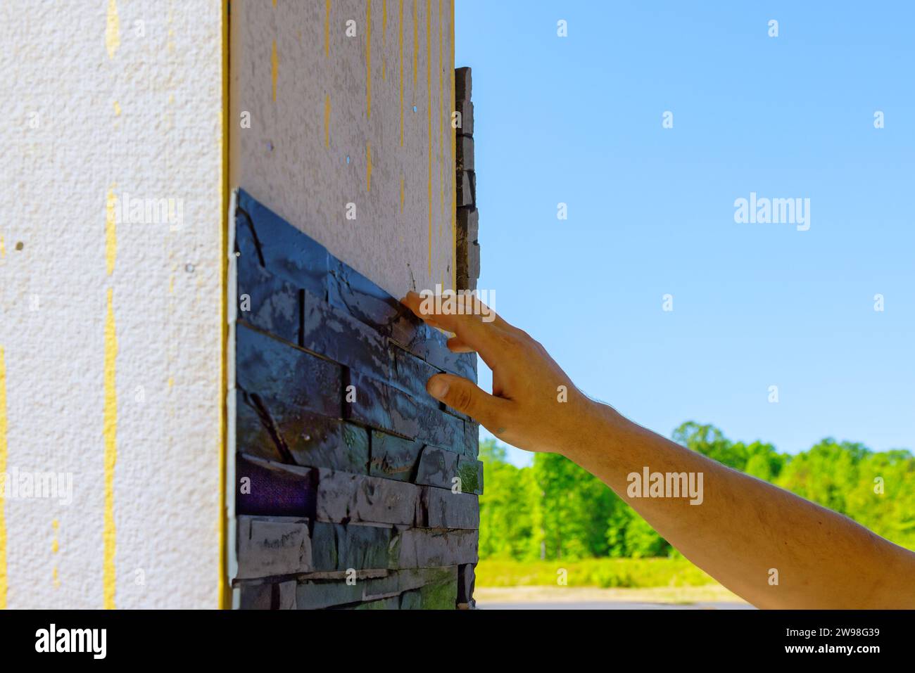 Tilers install facing tiles on building columns Stock Photo - Alamy