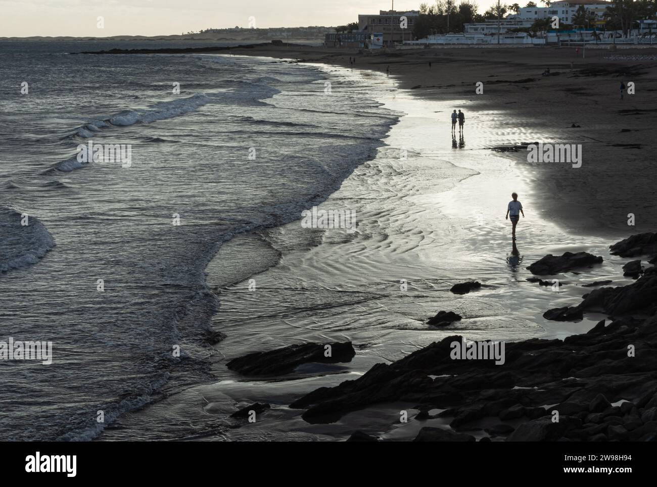 The waves hit the sandy beach where people are taking their morning ...