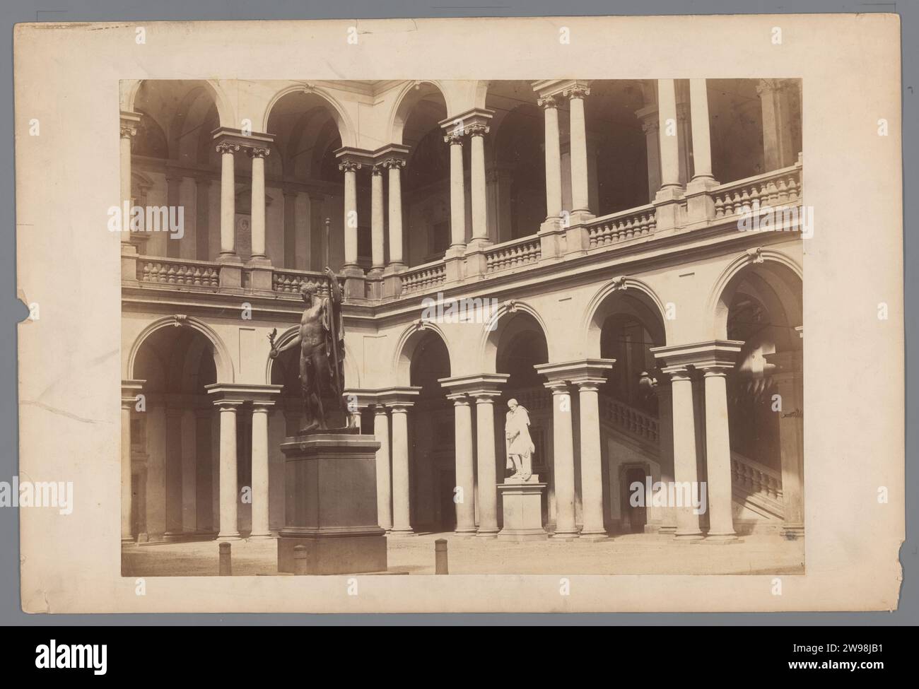 Courtyard with two statues of a building with a column gallery on two ...