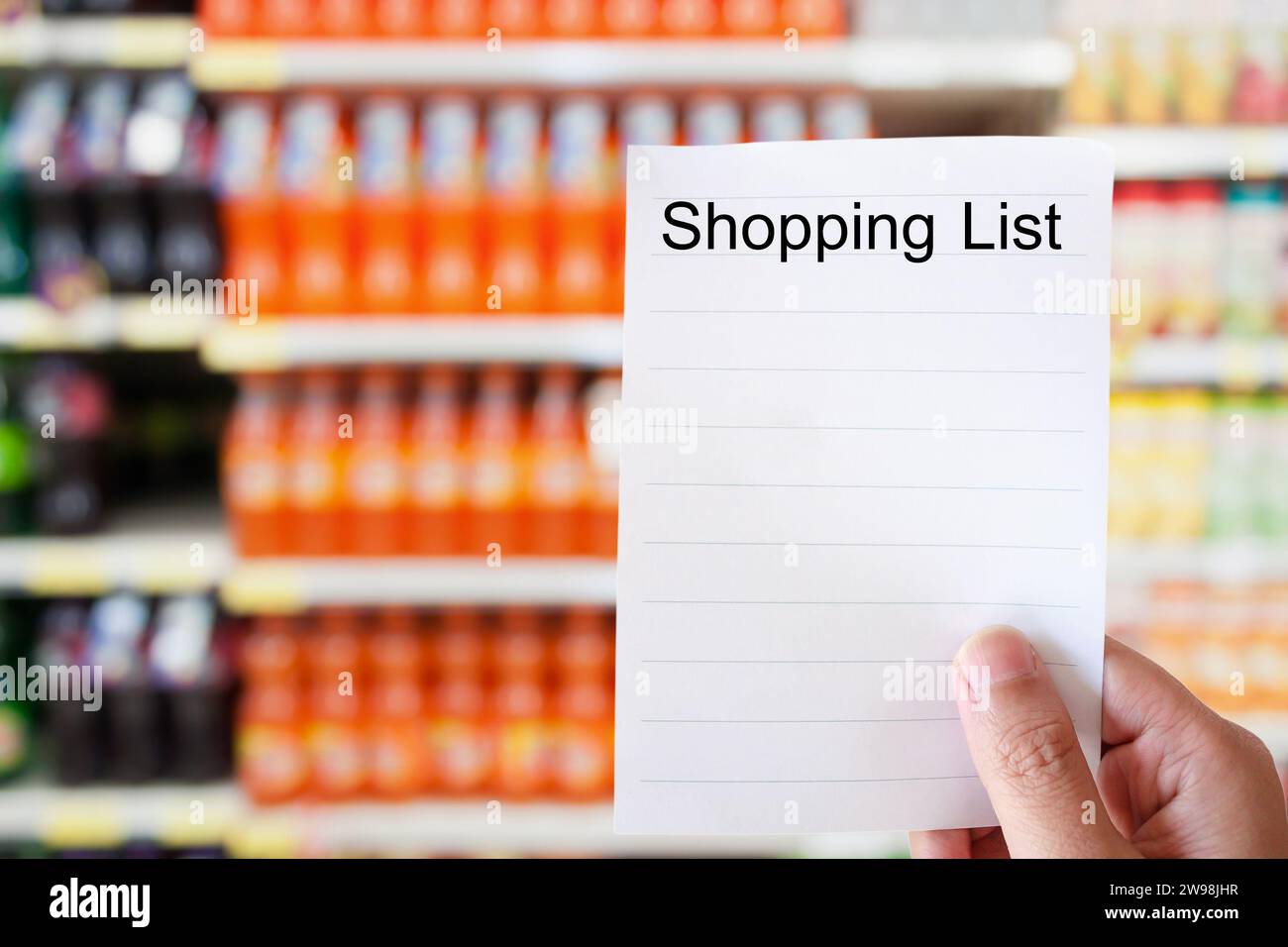 hand hold shopping list paper over soft drink bottles on shelves in ...