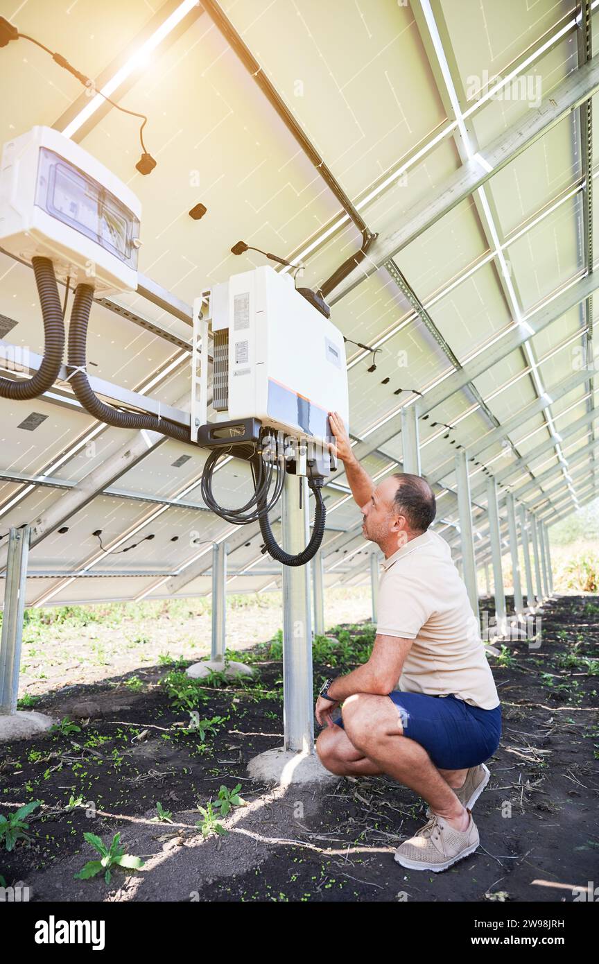 Male worker checking if solar inverter working right. Young man ...