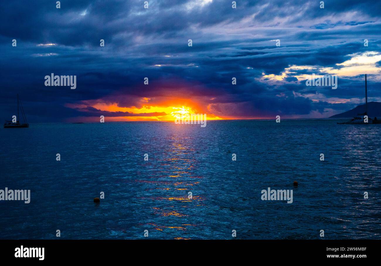 A Tahiti sunset revealed behind a dramatic cloudscape, with the ...