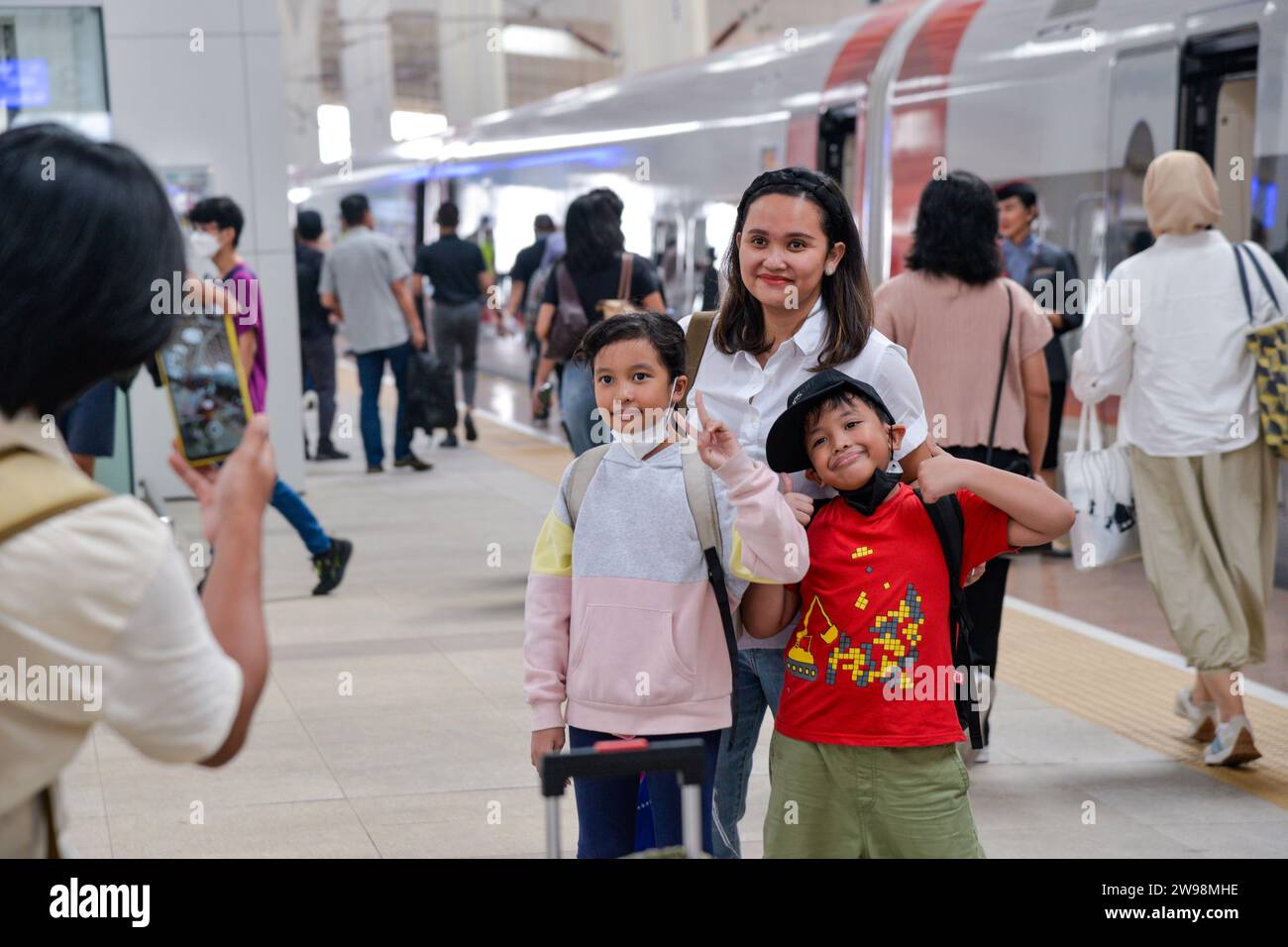 Jakarta, Indonesia. 25th Dec, 2023. Passengers pose for photos with a high-speed electrical ...