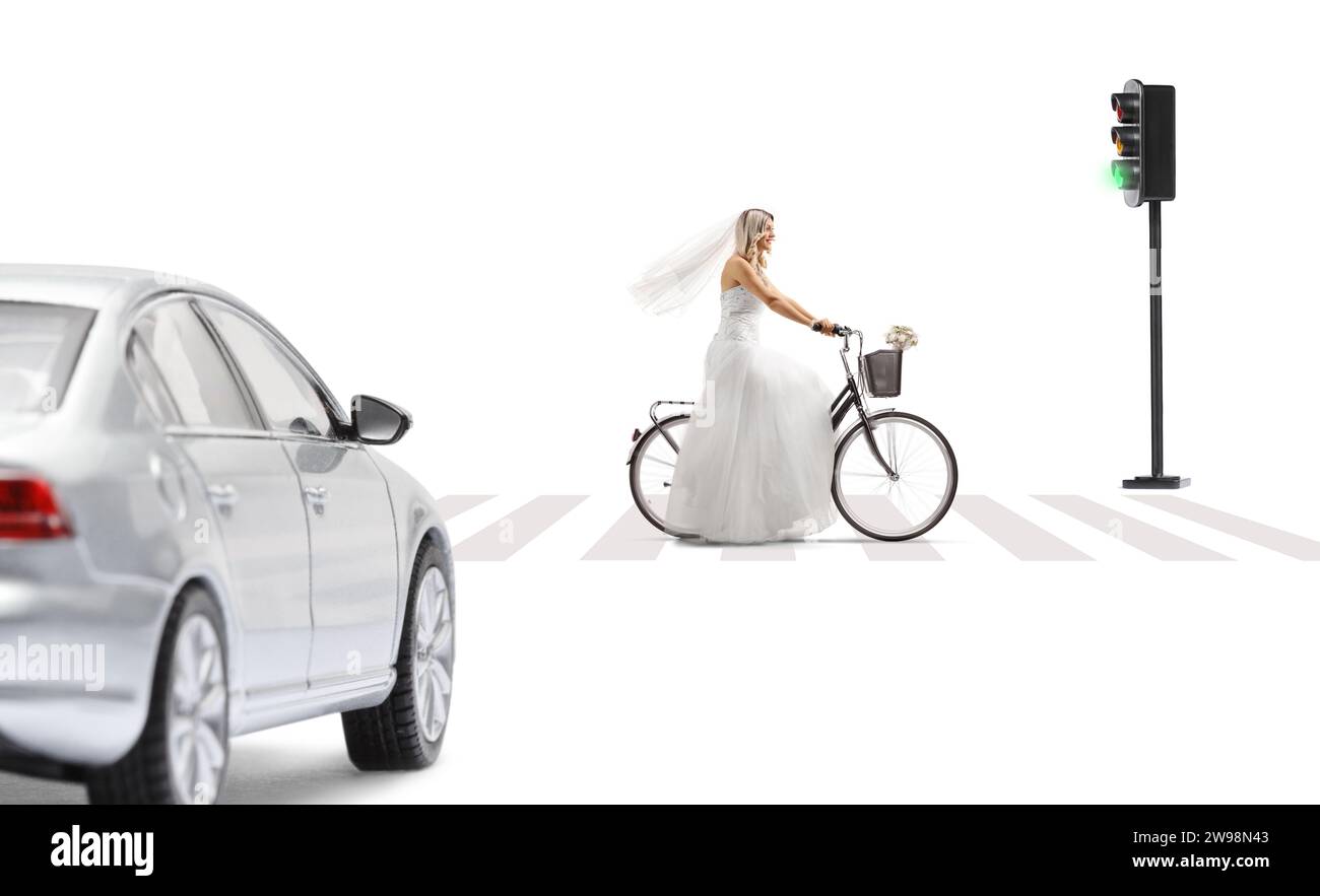 Bride riding a bicycle on a street in front of a car isolated on white ...