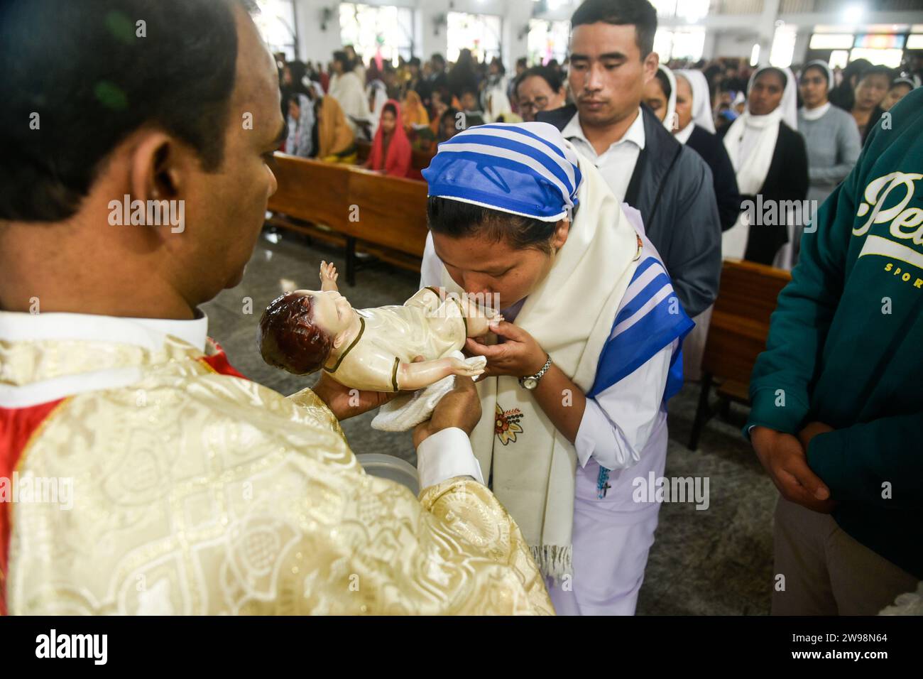 GUWAHATI,INDIA- DECEMBER 25: Devotee kisses the baby idol of Jesus ...
